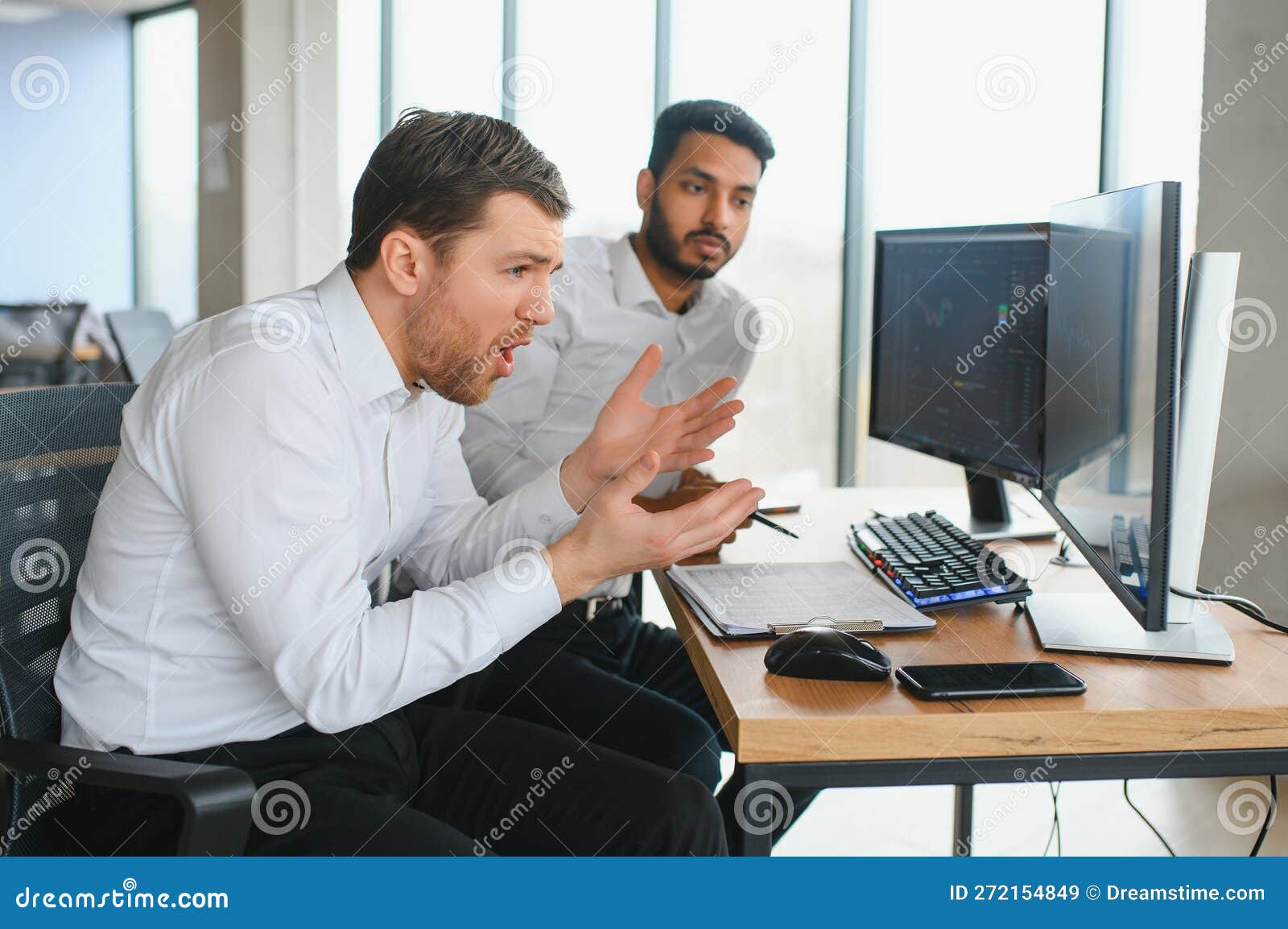 Two Men Traders Sitting at Desk at Office Together Looking at Data ...