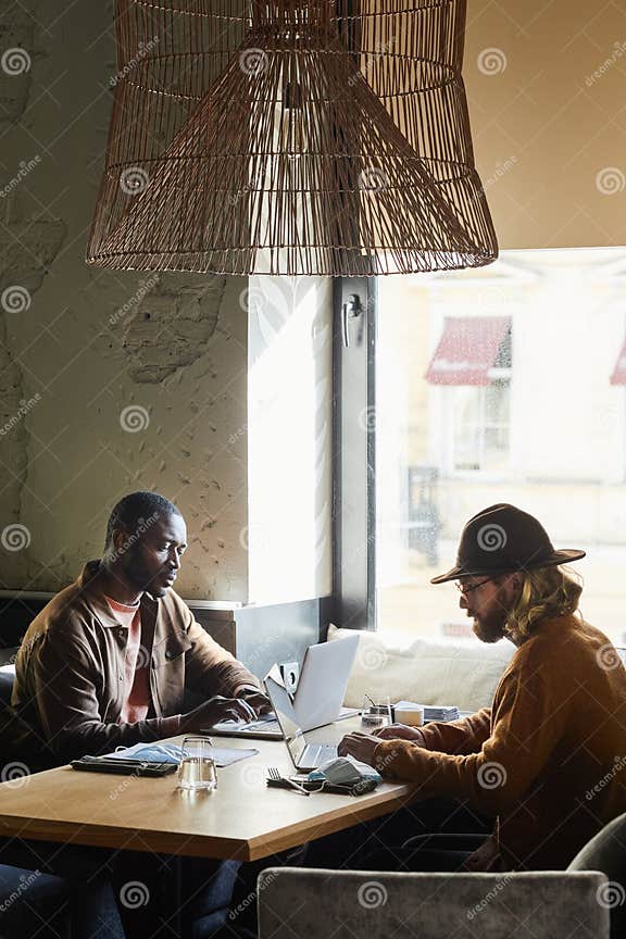 Two Men Using Computers at Cafe Table Stock Image - Image of ...