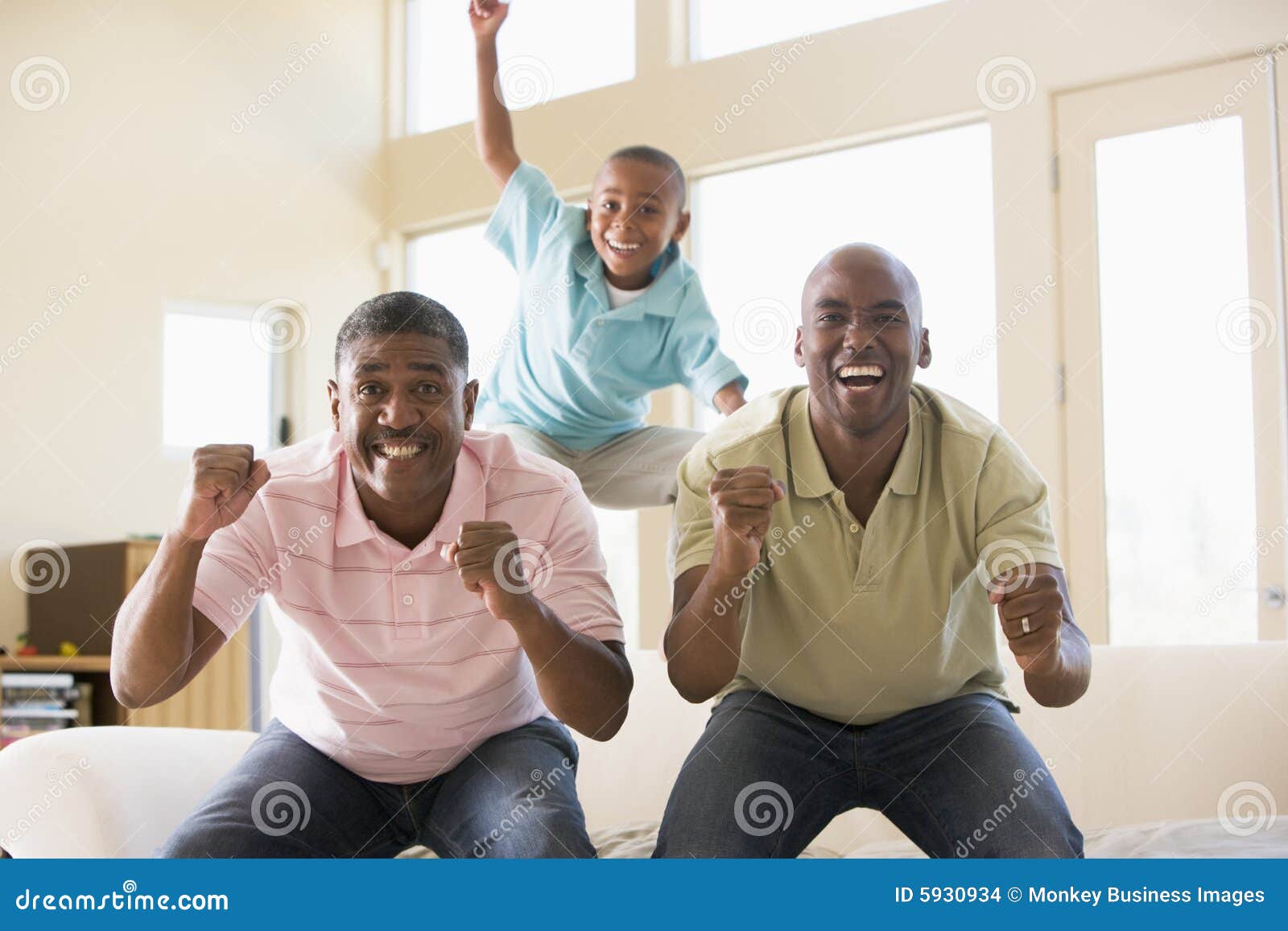 Two Men and Young Boy in Living Room Cheering Stock Photo - Image of ...