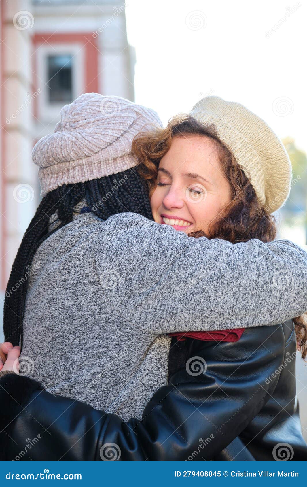 Two Multiracial Female Happy Friends Hugging Each Other On City Street