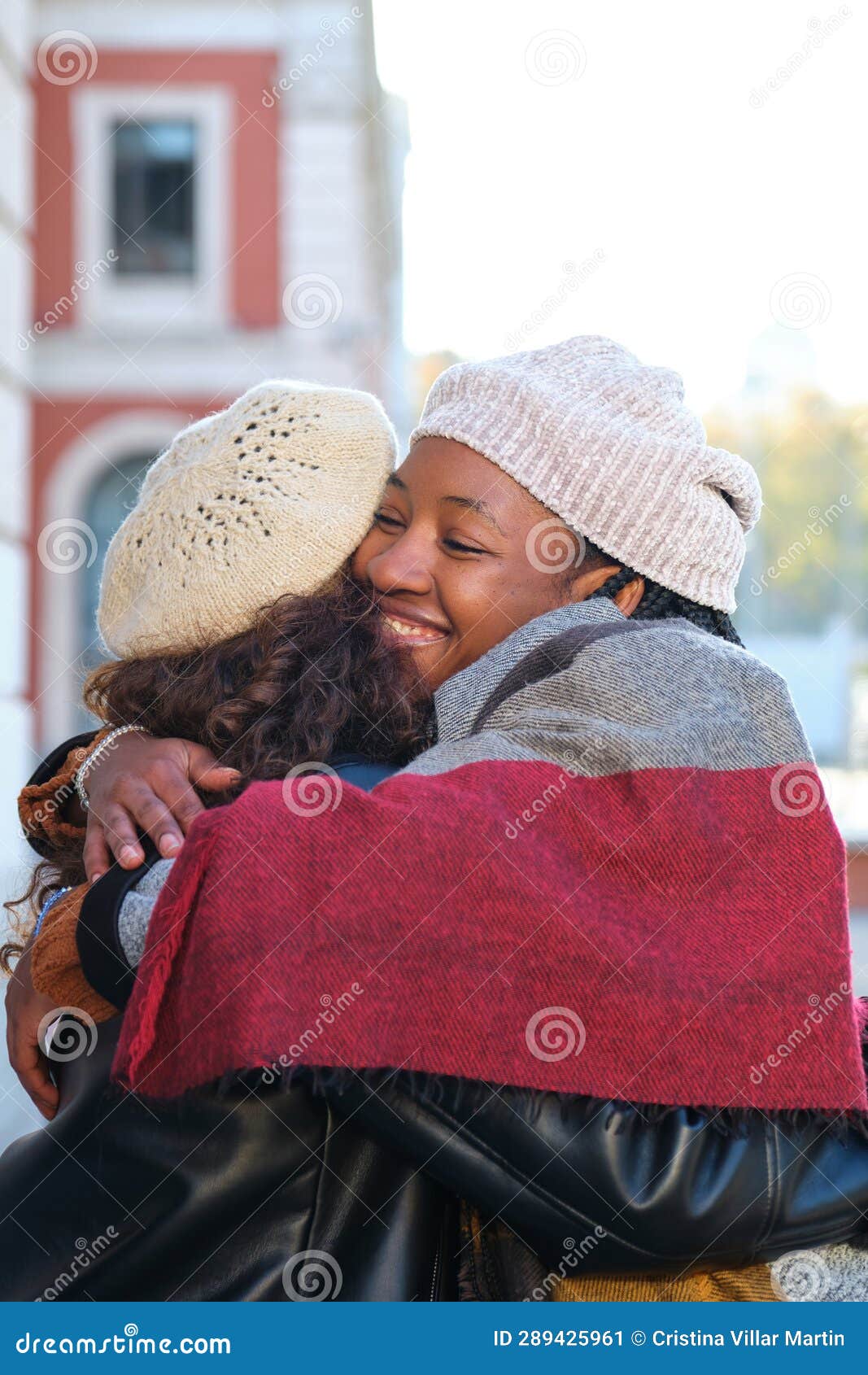 Two Multiracial Female Happy Friends Hugging Each Other On City Street