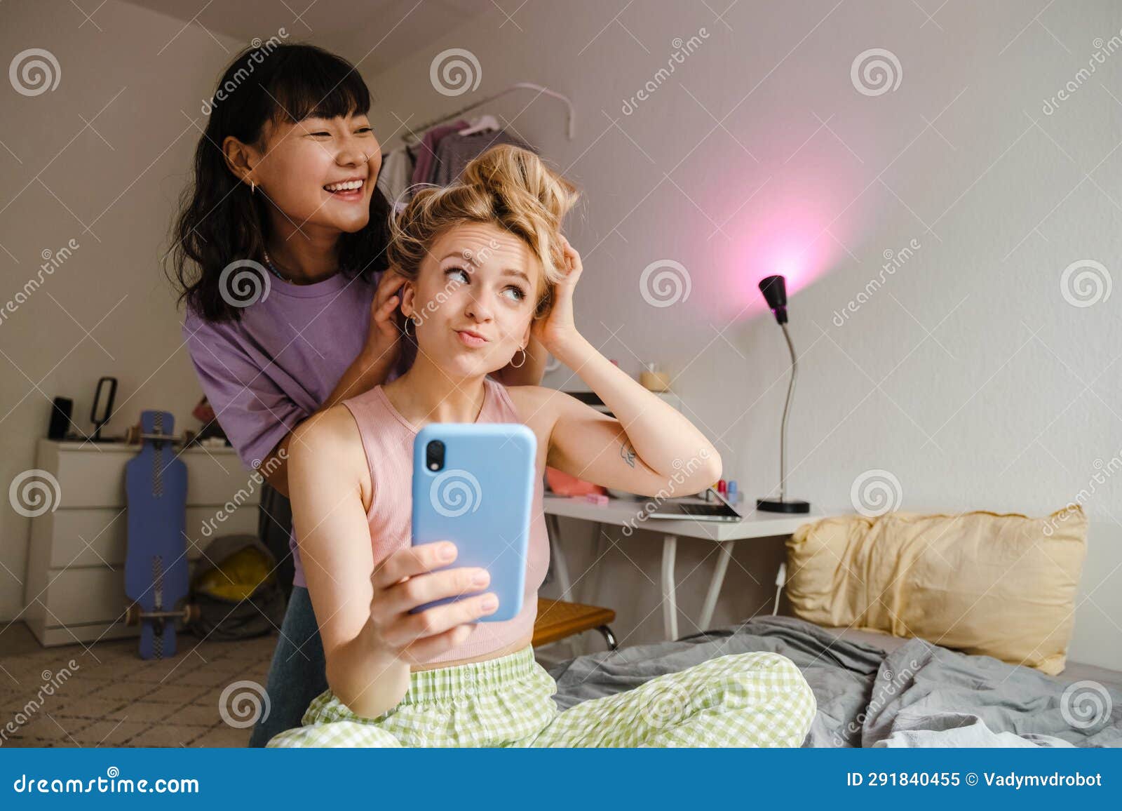 Two Multiracial Girls Using Mobile Phone while Doing Hairstyle Stock ...