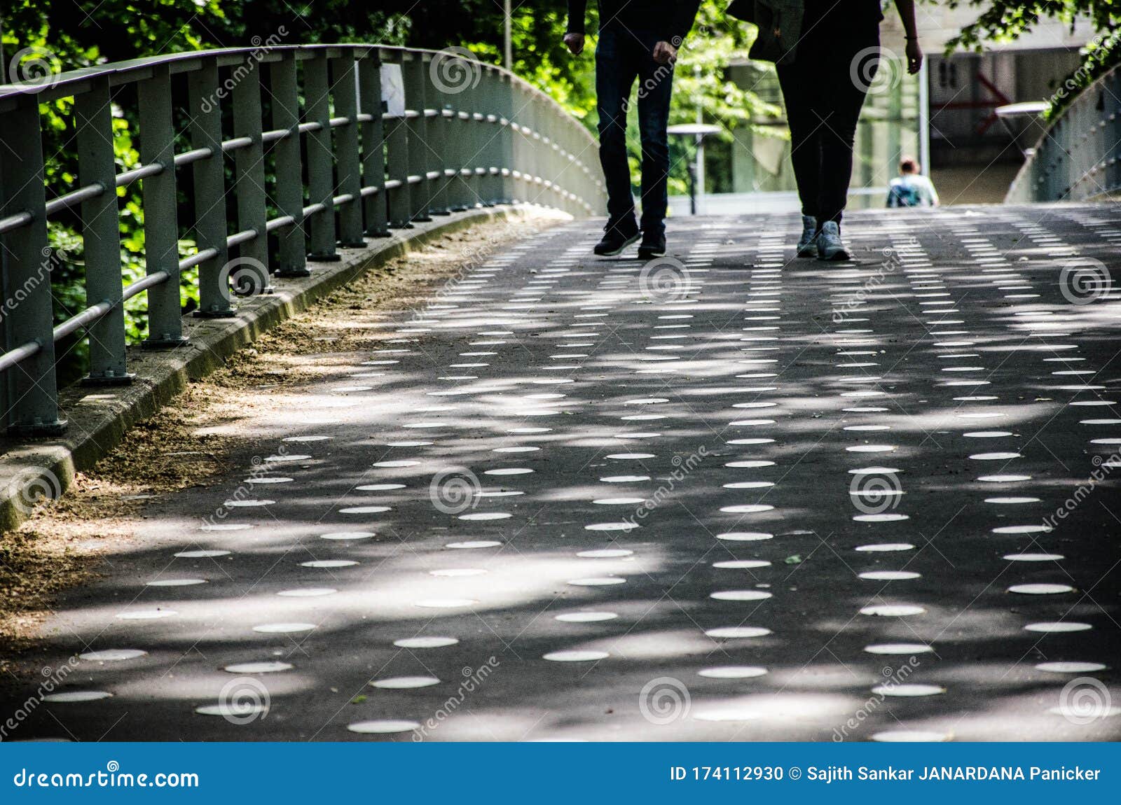 Two Pair of Legs Walking Over a Bridge with Sunlight Making a Pettern ...