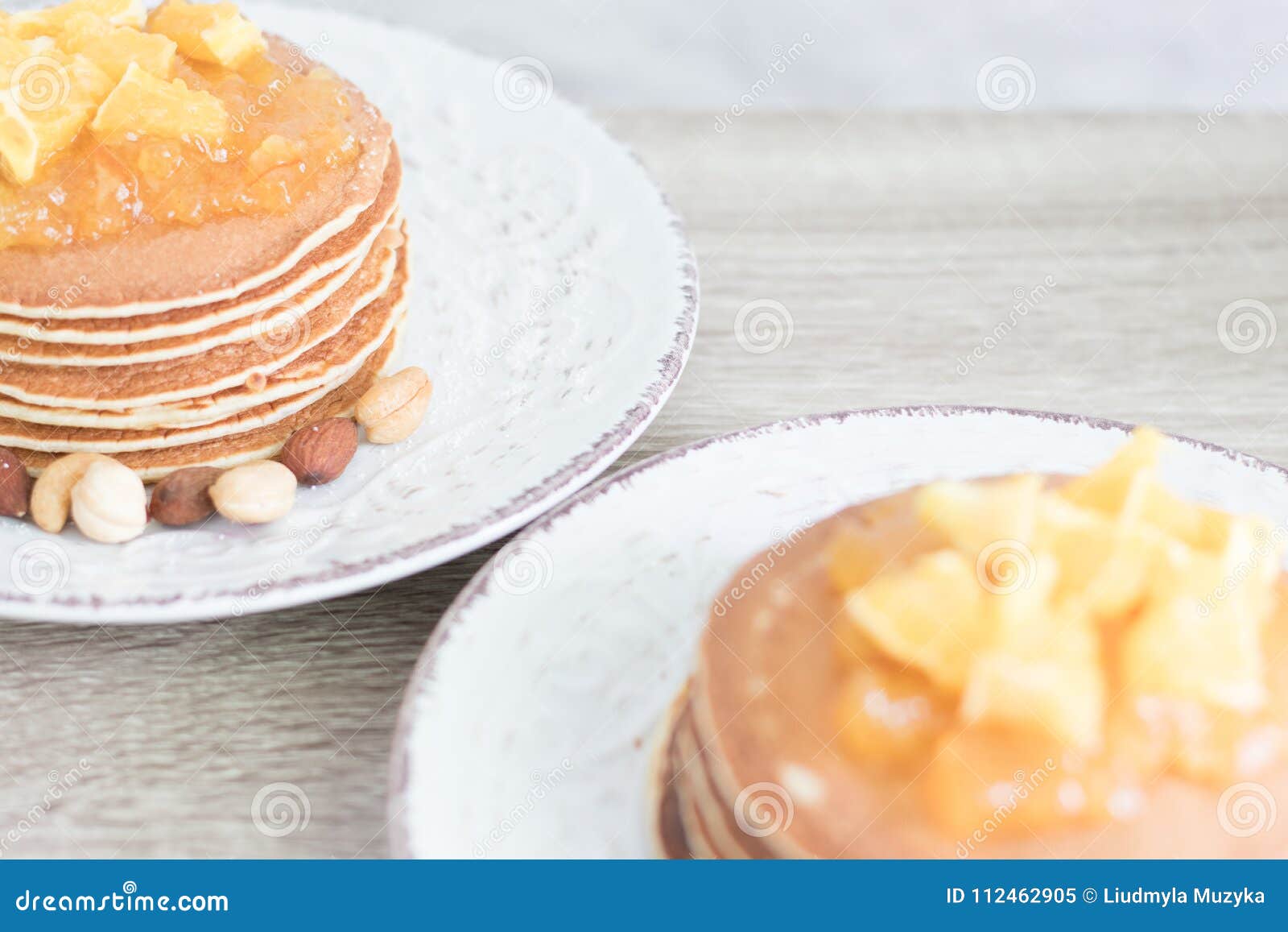 Two Pancakes Plates with Orange Jam and Nuts on Wooden Table. Closeup ...