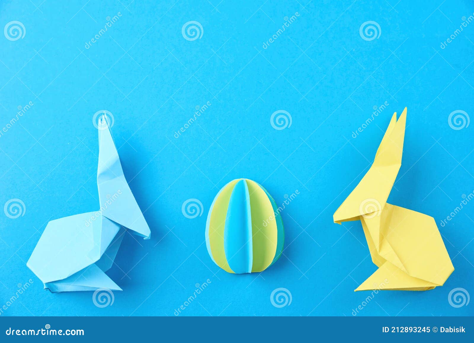 Two Paper Origami Esater Rabbits and Colored Egg on Blue Background ...