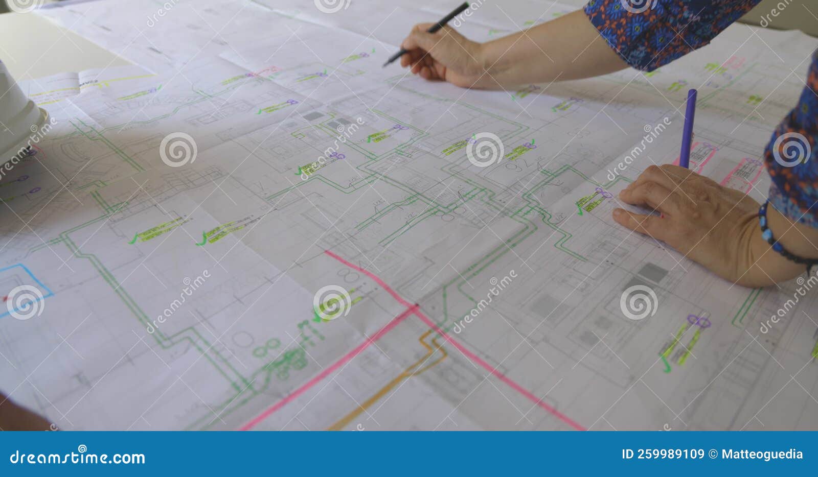 Two People Analyze a Technical Drawing with Highlighters in a Technical ...