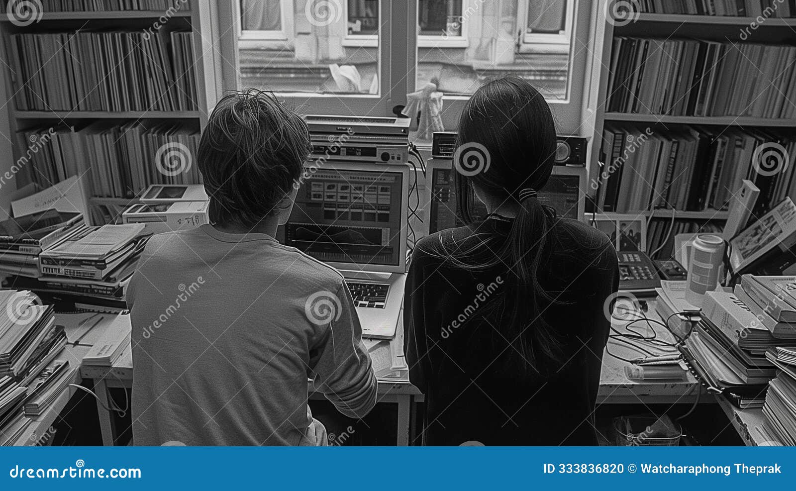 Two People Collaborating at a Cluttered Desk in a Home Office Stock ...
