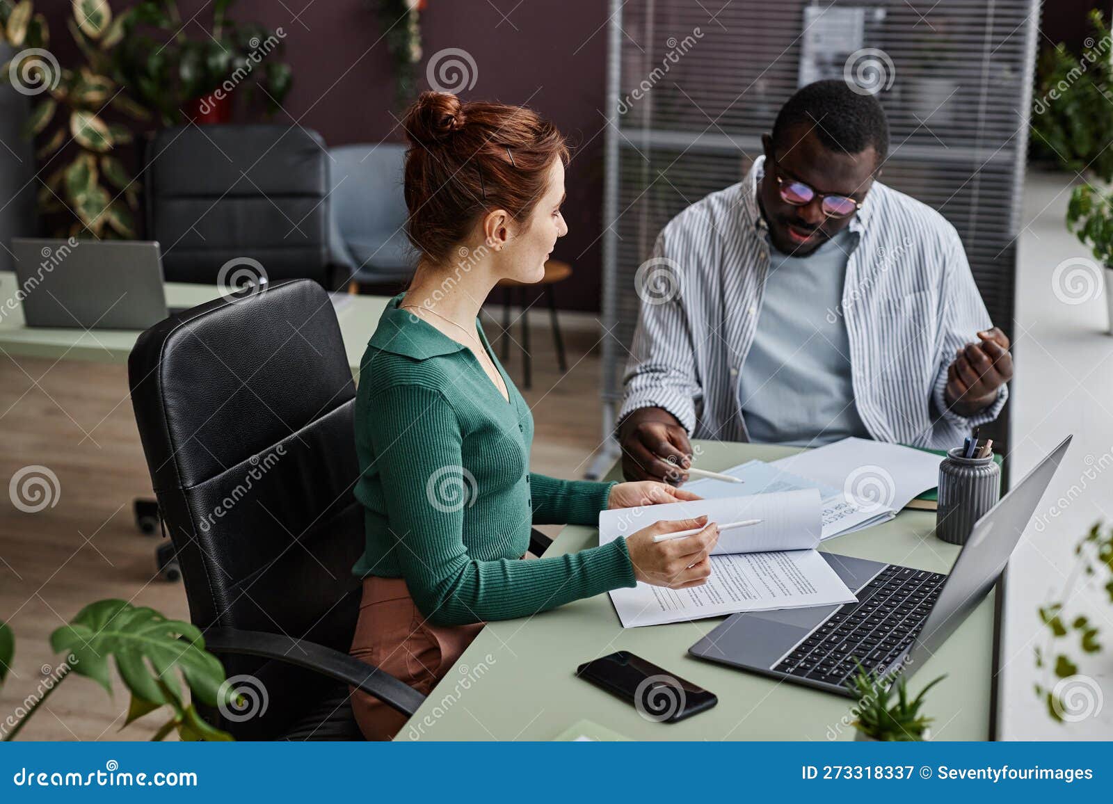 Two People Discussing Project and Reading Documents at Workplace Stock ...
