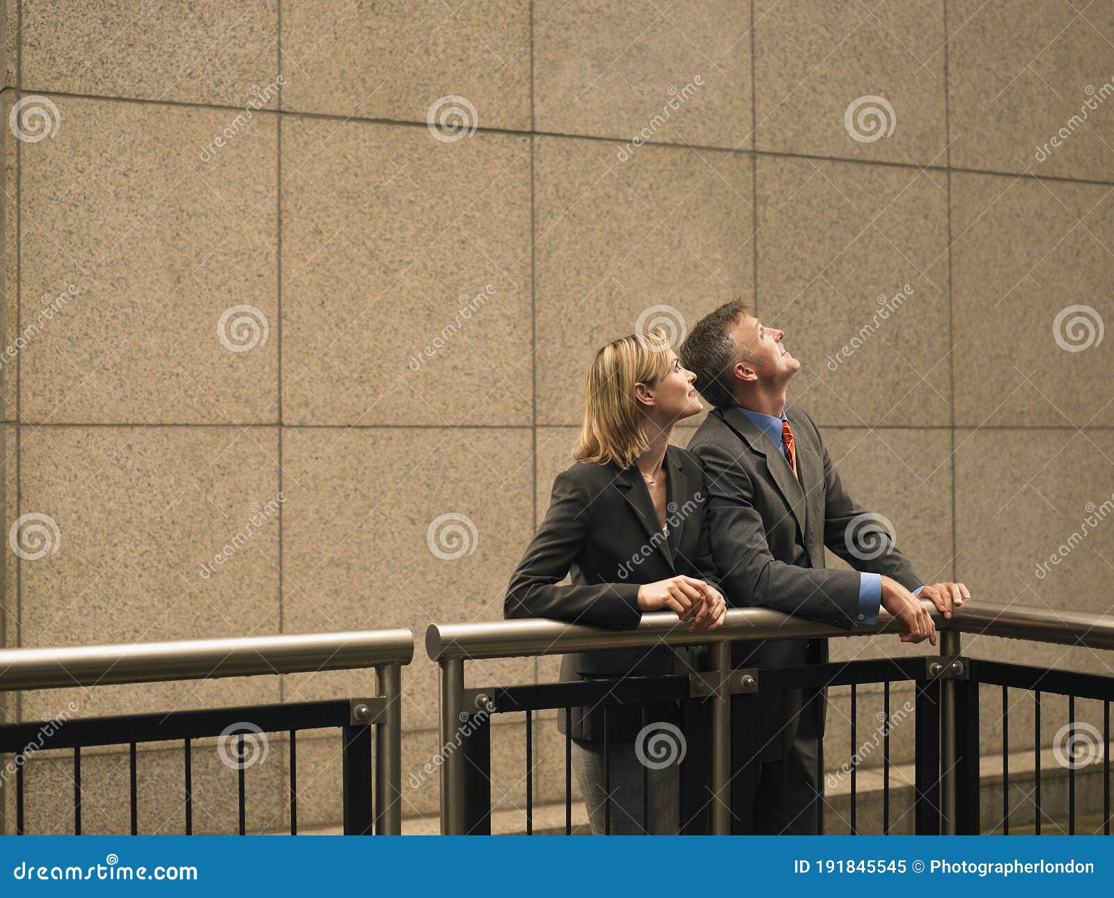 Two People Leaning Against Railing Looking Up Stock Image - Image of ...
