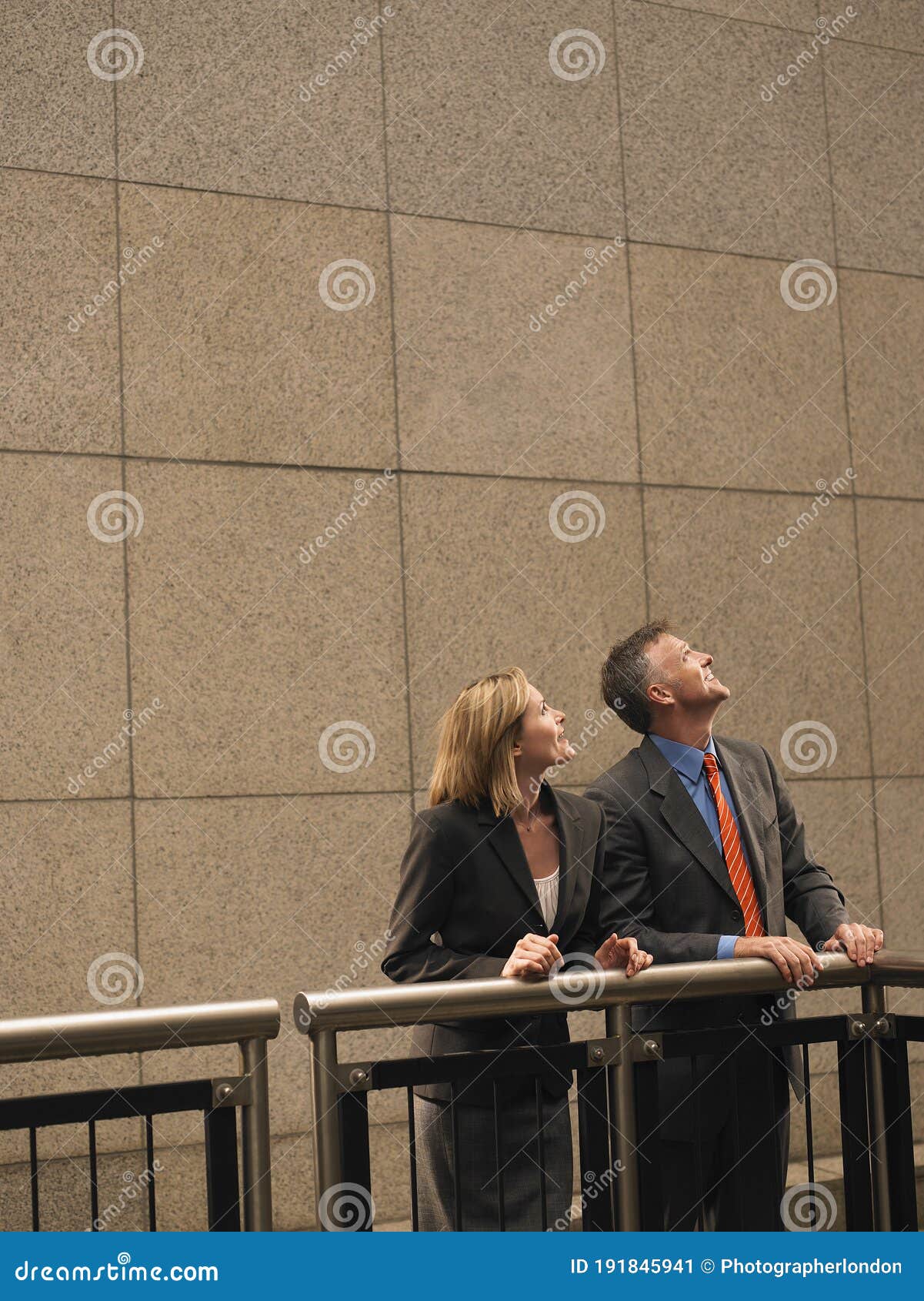 Two People Leaning Against Railing Looking Up Stock Image - Image of ...