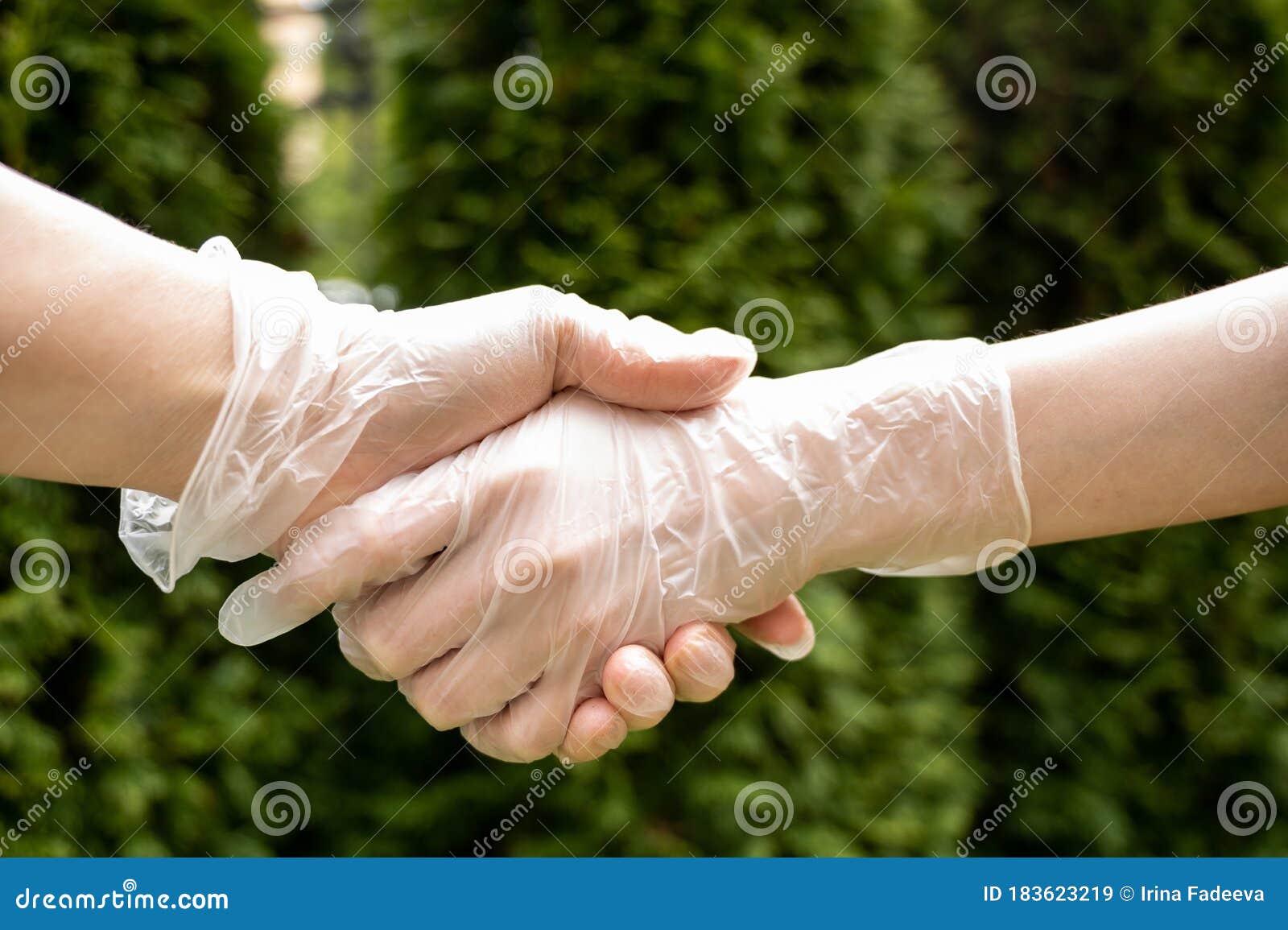 Two People Shake Hands in Rubber Gloves Against a Background of Green ...