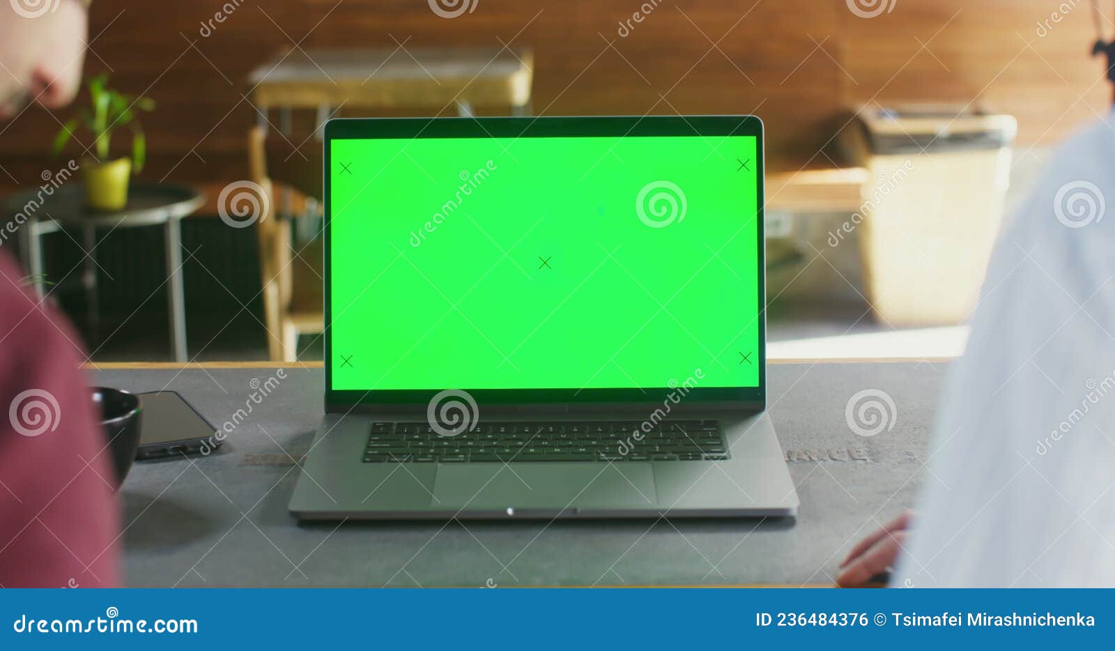Two People Sit at a Table in a Cafe in Front of an Laptop with a Green ...