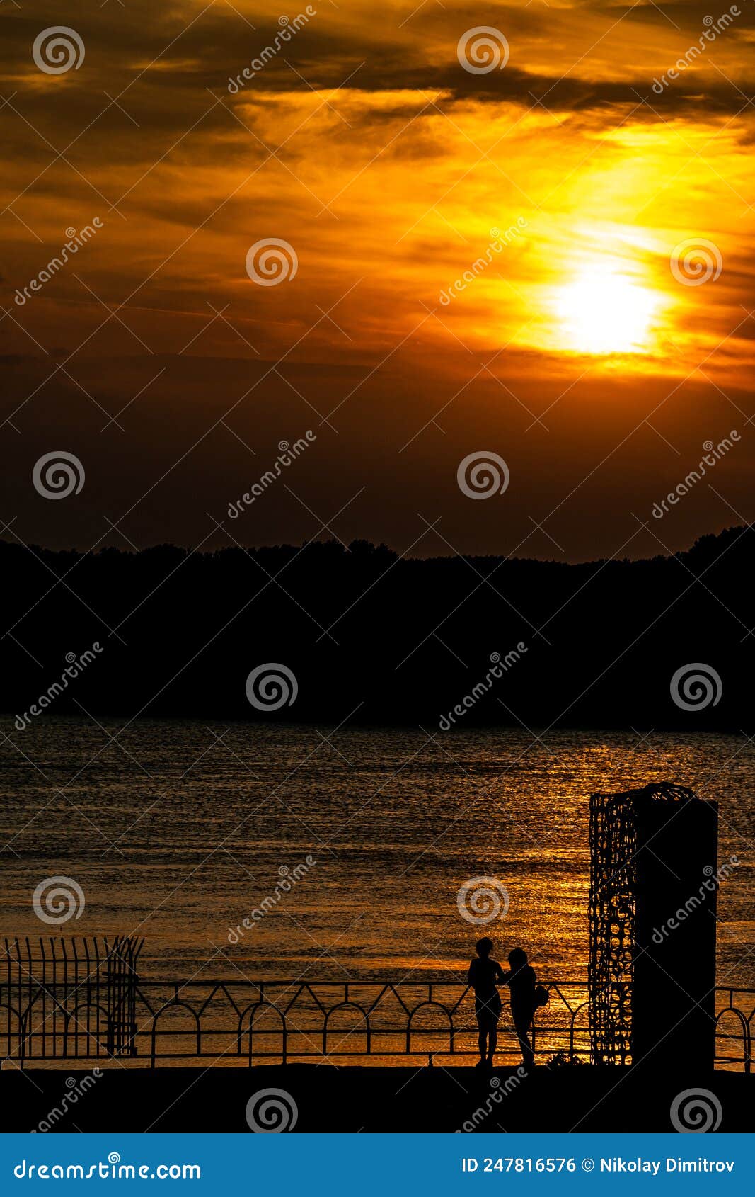 Two people at sunset stock photo. Image of reflection - 247816576