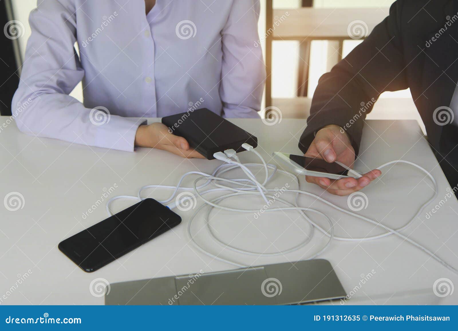 Two People Using Two Mobile Phone Sharing USB Power Bank on a Table To ...