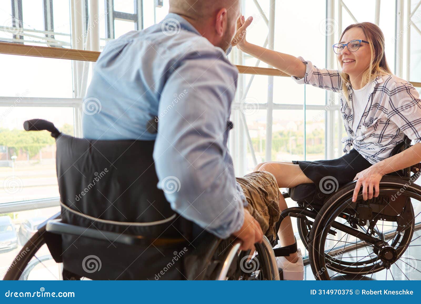 Two People in Wheelchairs Bonding Over a High-five in a Modern Office ...