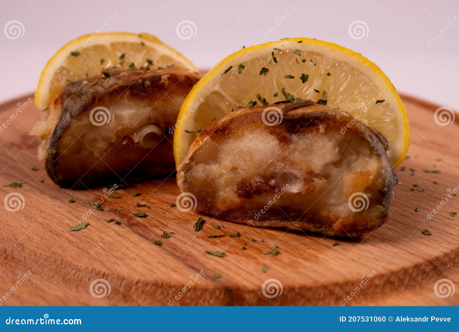 Two Pieces of Fish Baked and Garnished with Lemon Stock Photo - Image ...