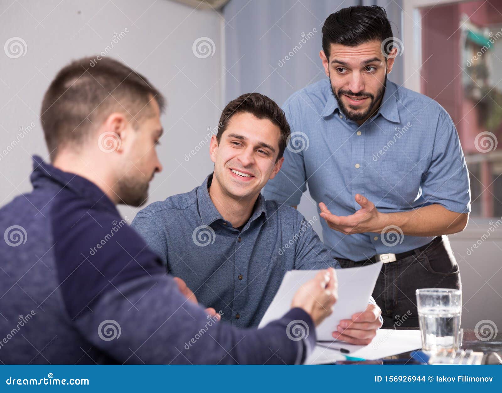 Two Positive Men Helping Friend with Documents at Table Stock Photo ...