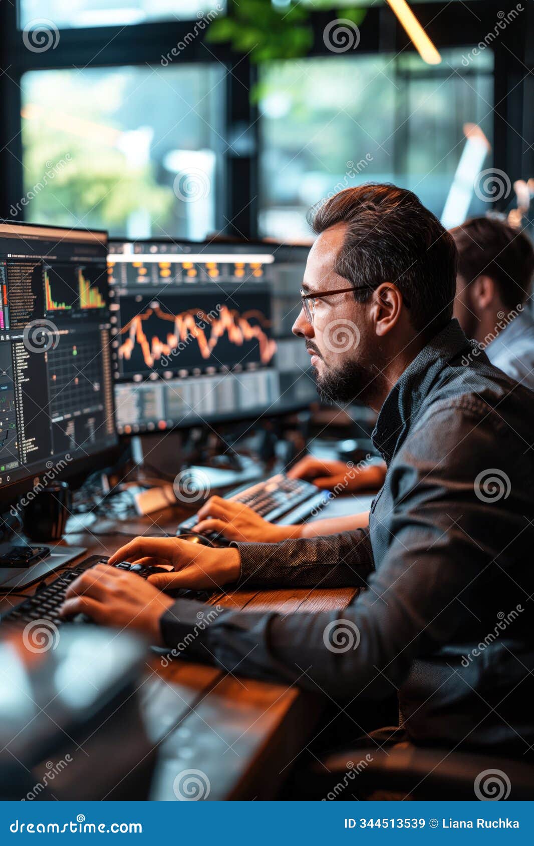 Two Professionals Collaborating at a Desk with Monitors Showcasing ...