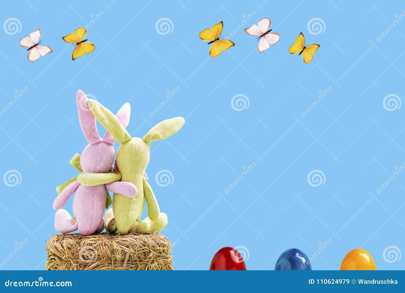 Two Rabbits on a Straw Bale with Easter Eggs and Butterflies Stock ...