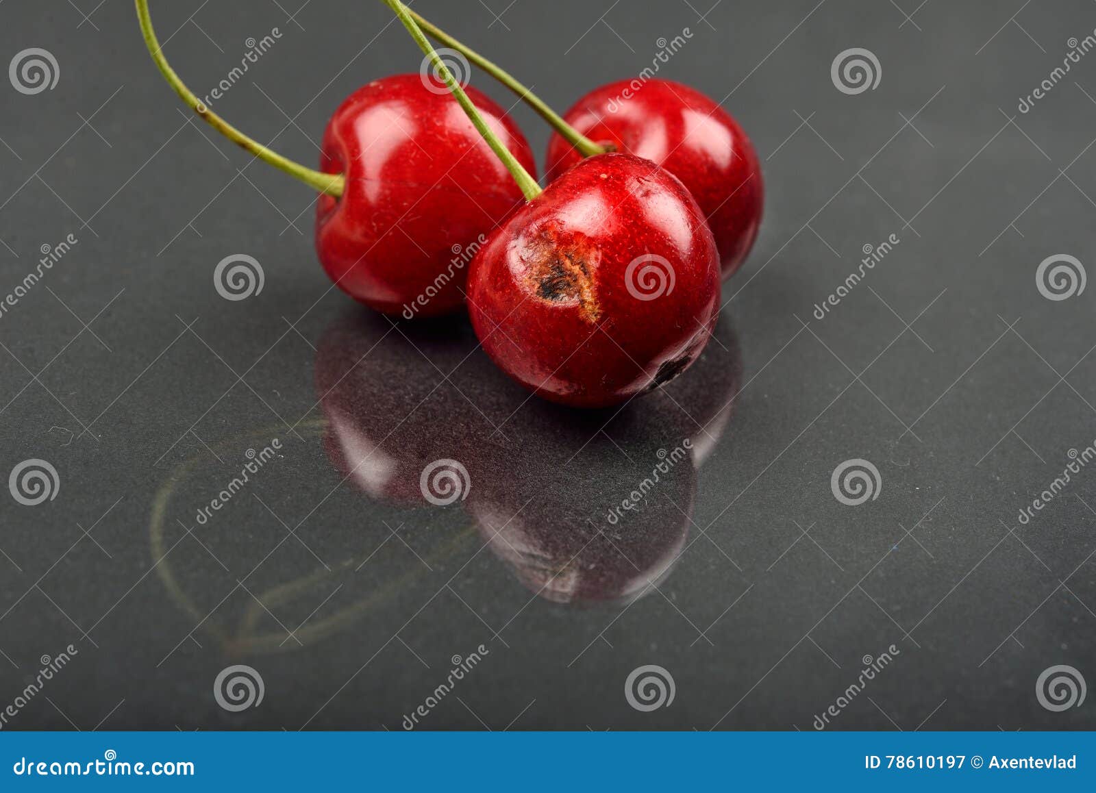 Two Red Cherries and One Broken Against Reflective Black Background ...