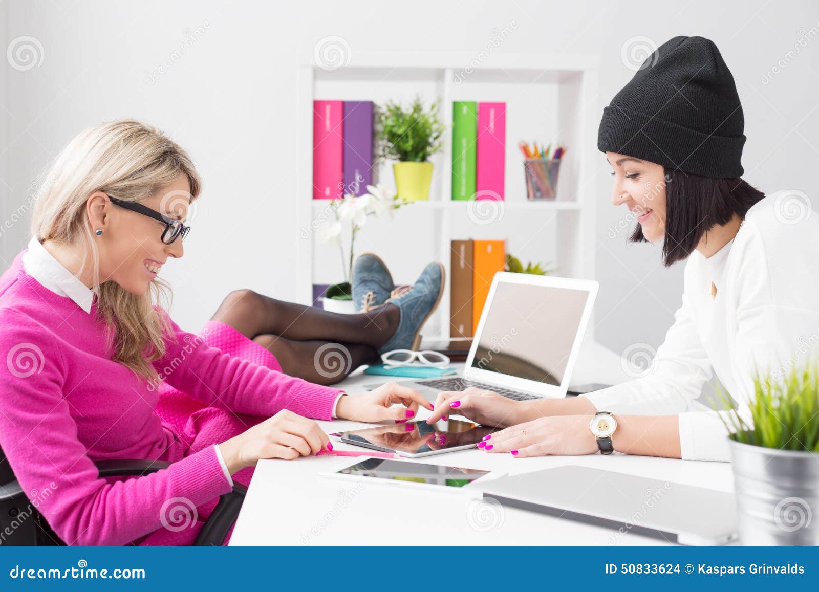 Two Relaxed Creative Young Women Using Tablet Computer in the Office ...
