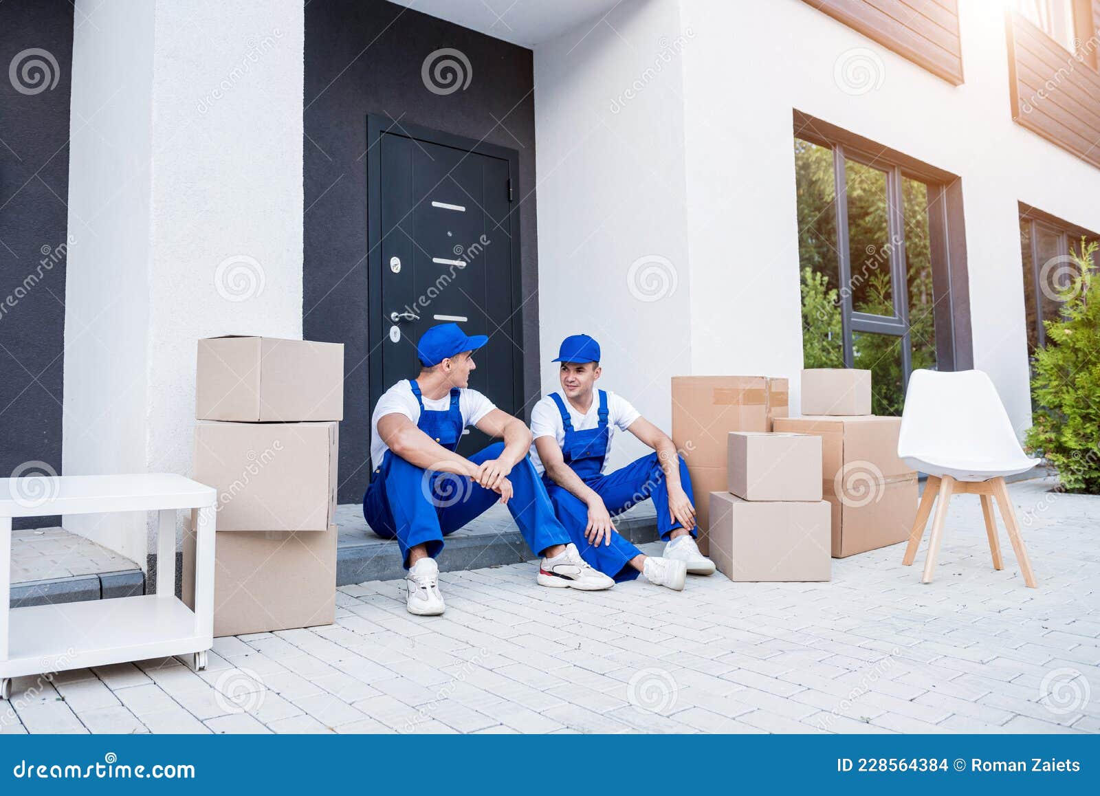 Two Removal Company Workers Have a Break while Sitting on the Step ...