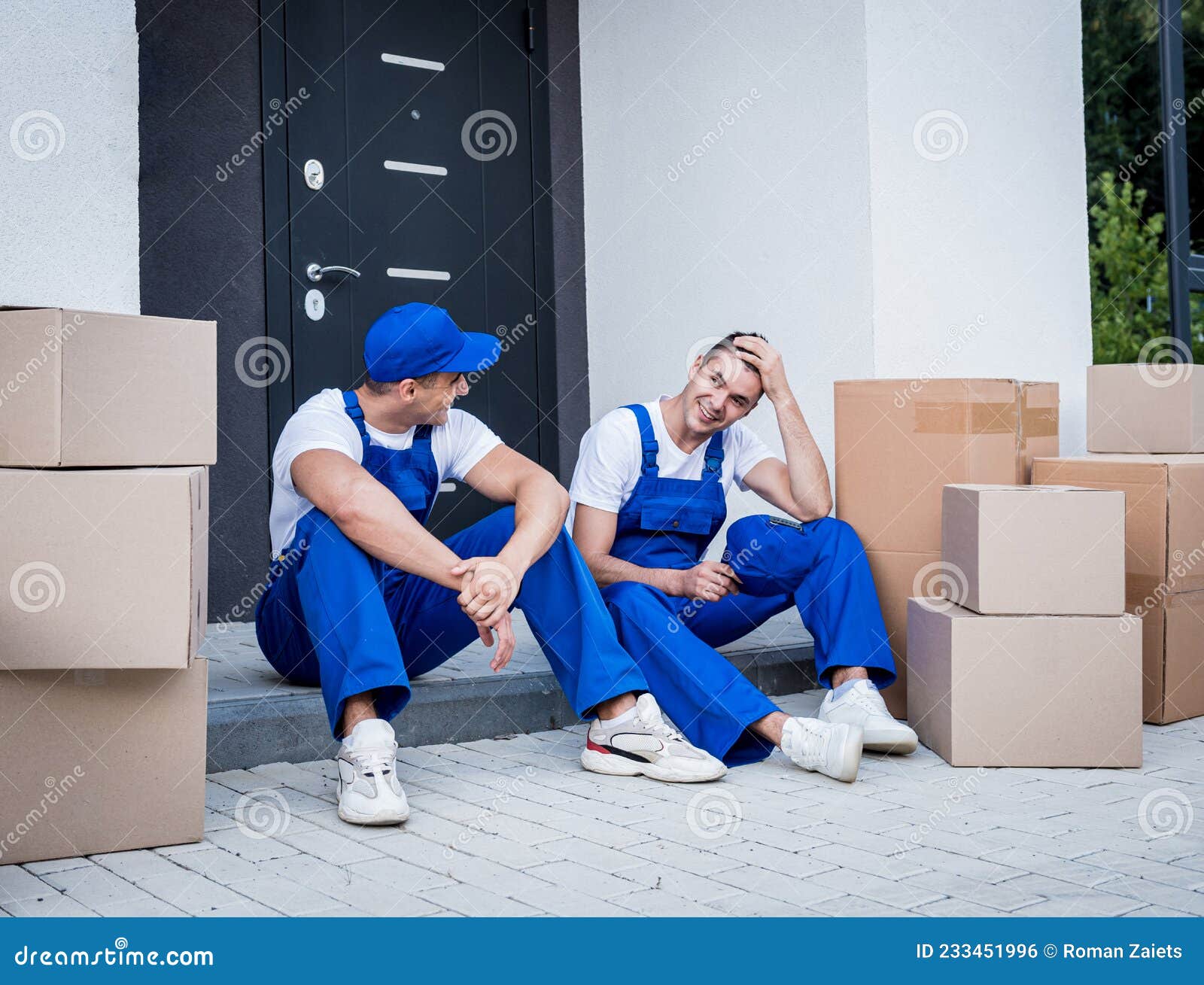 Two Removal Company Workers Have a Break while Sitting on the Step ...