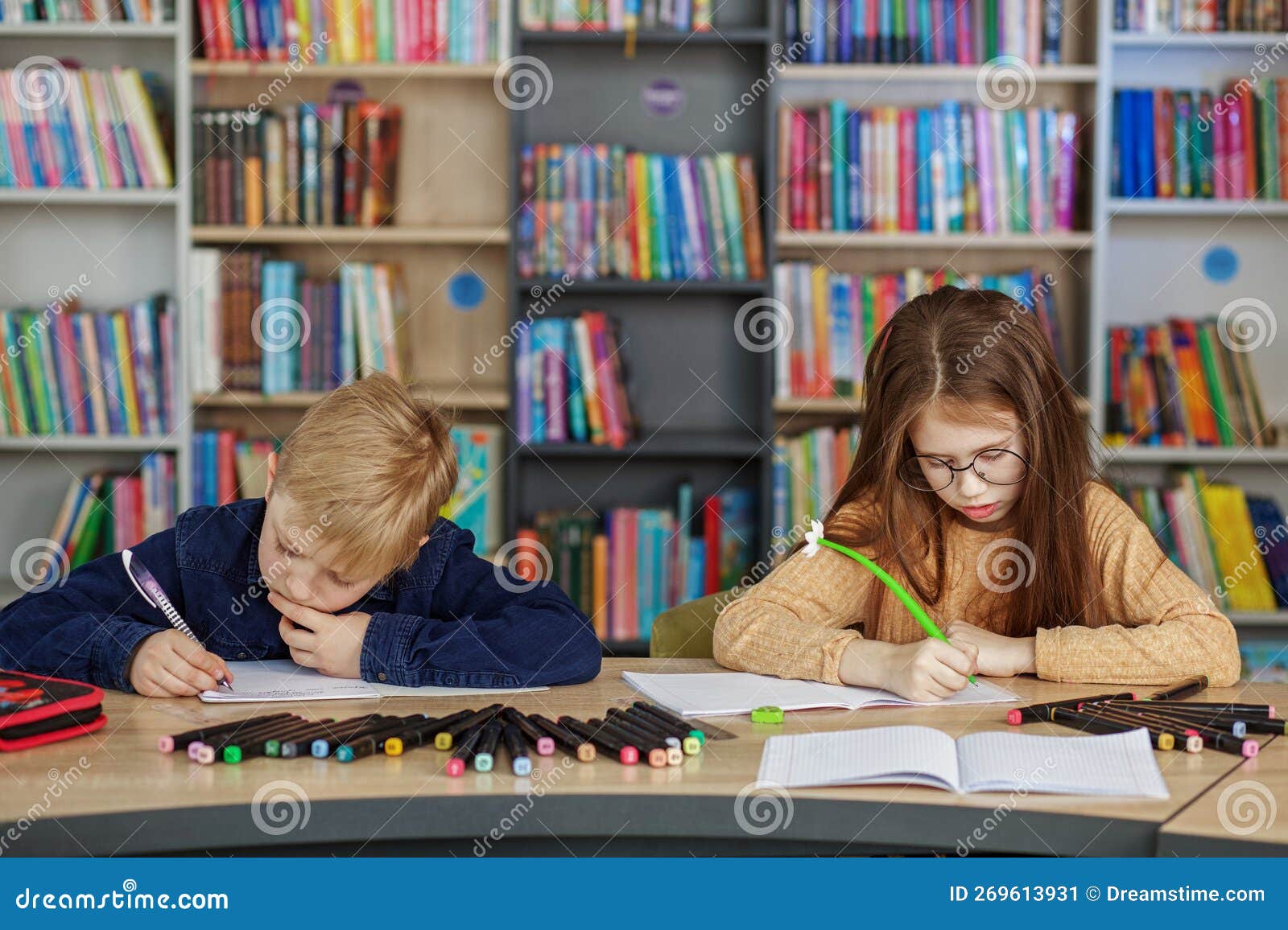 Two Schoolchildren Write and Draw Sitting at Table in Library ...