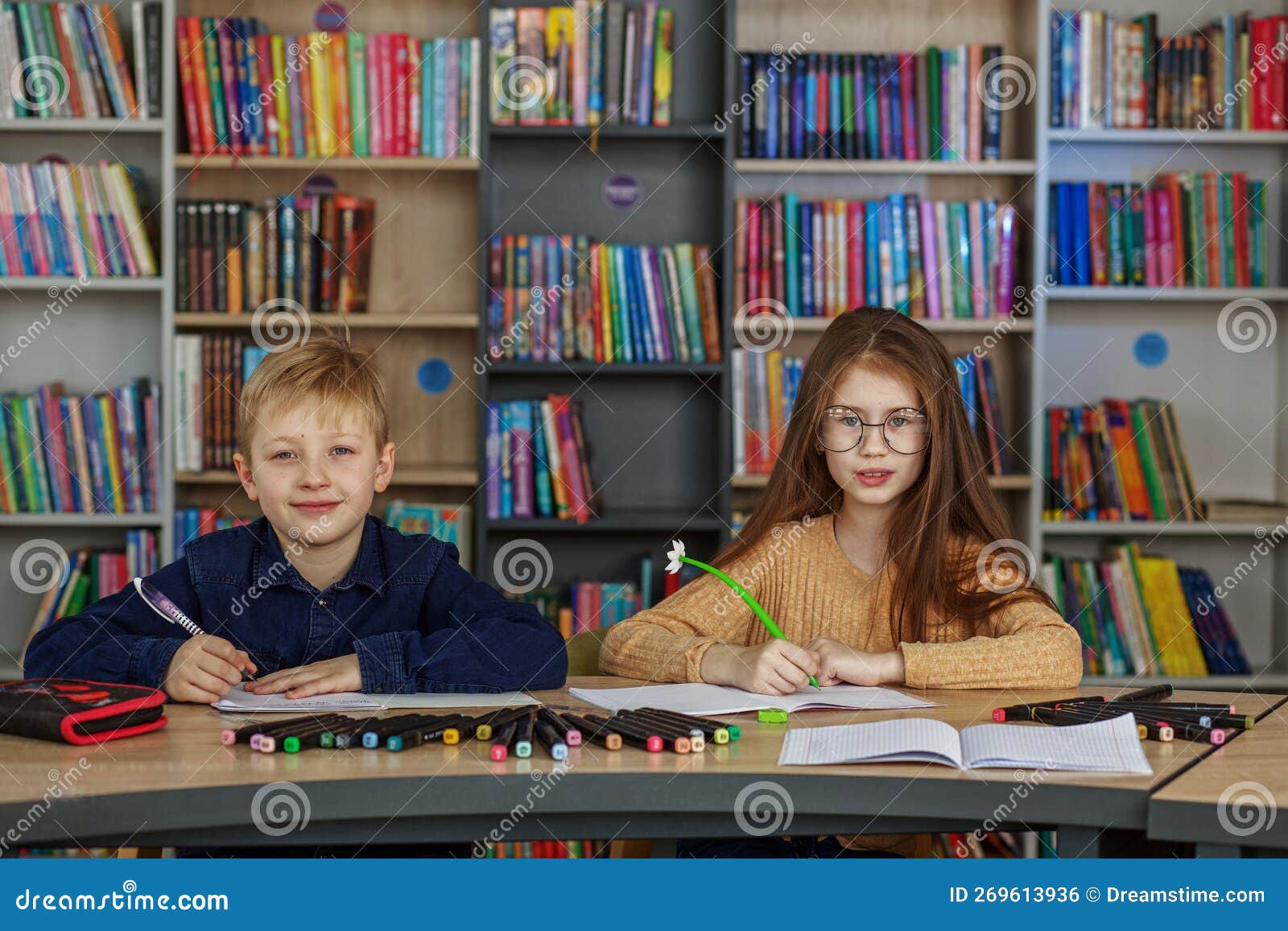 Two Schoolchildren Write and Draw Sitting at Table in Library ...
