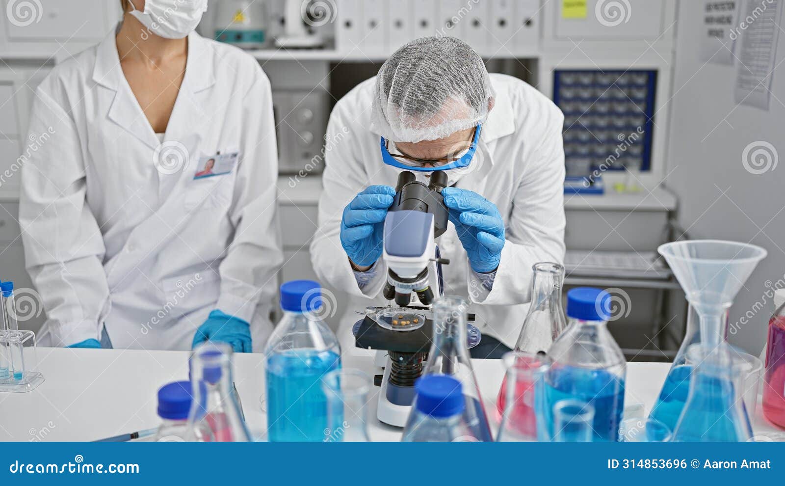 Two Scientists Wearing Medical Mask and Gloves Using Microscope at ...
