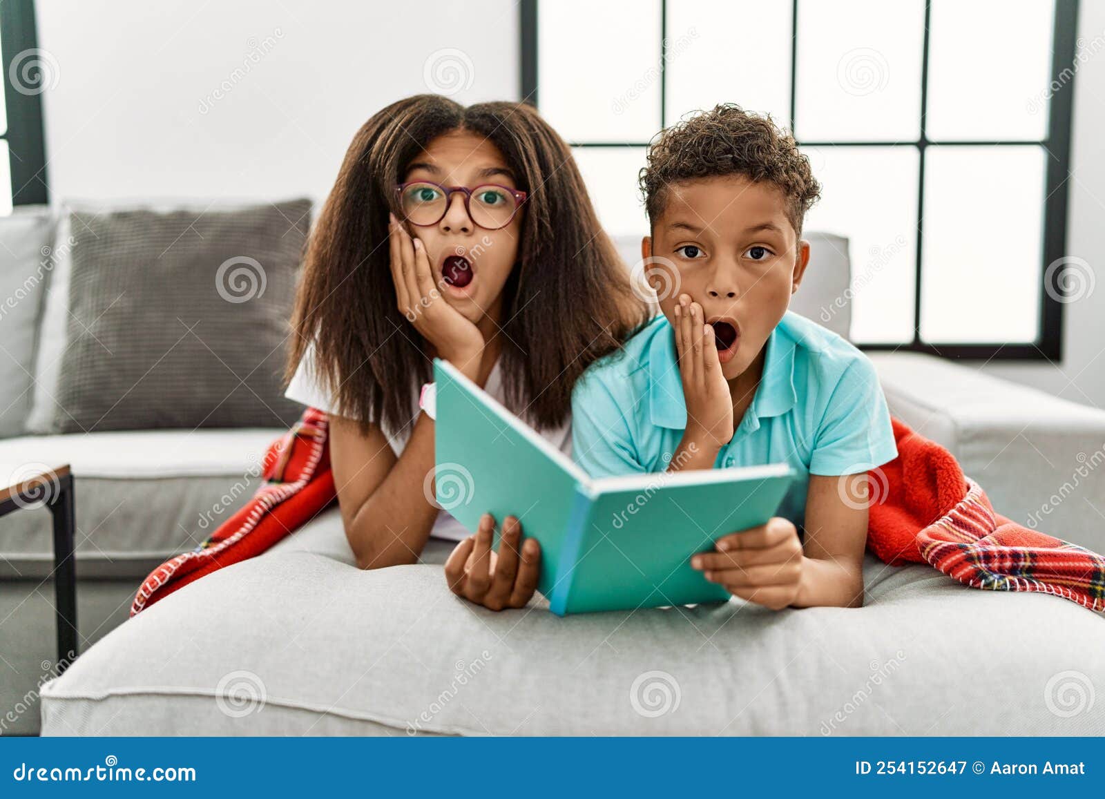 Two Siblings Lying on the Sofa Reading a Book Afraid and Shocked ...