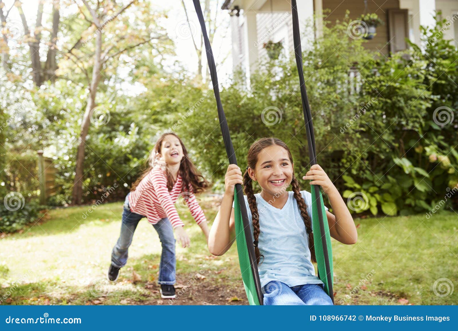 Two Sisters Having Fun on Garden Swing at Home Stock Photo - Image of ...