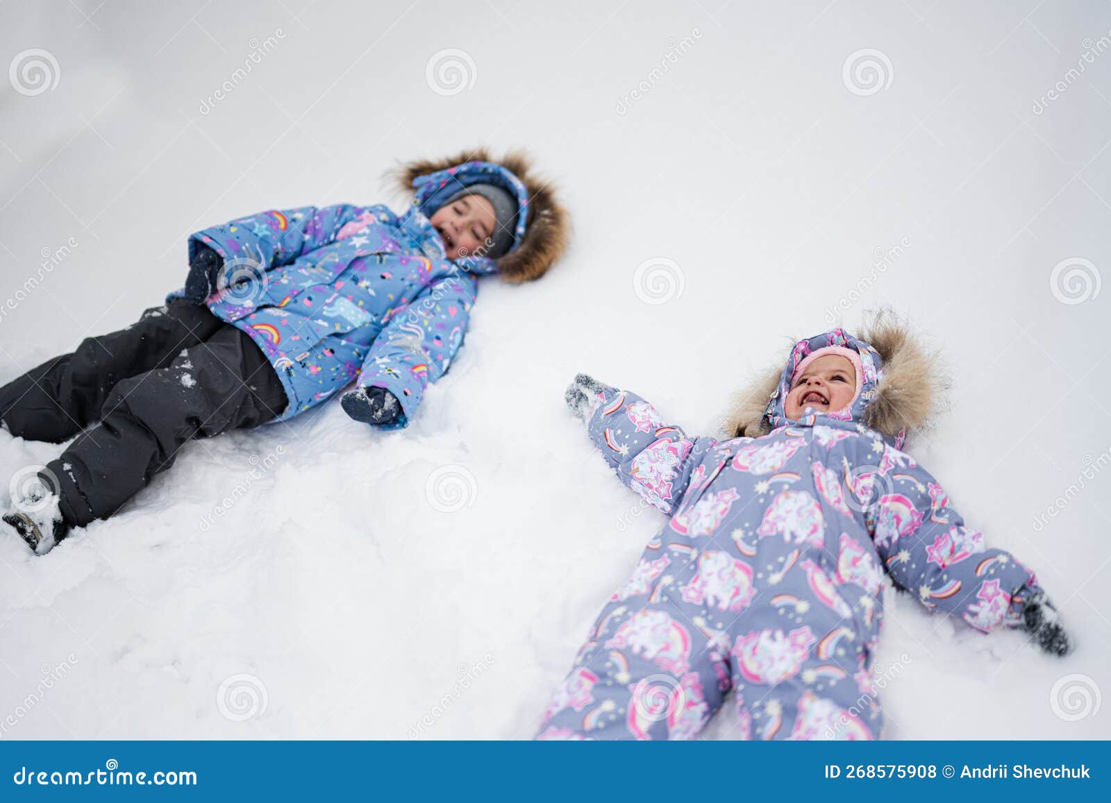 Two Sisters Making Snow Angel while Lying on Snow Stock Photo - Image ...