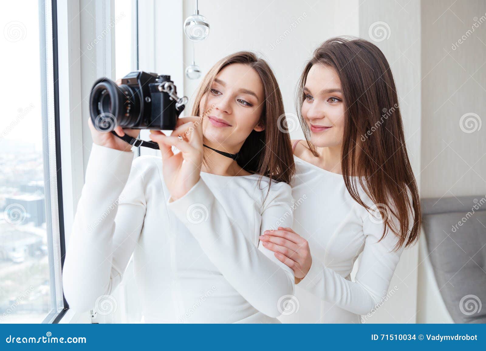 Two Sisters Twins Taking Photos Using Camera Near Window Stock Photo ...