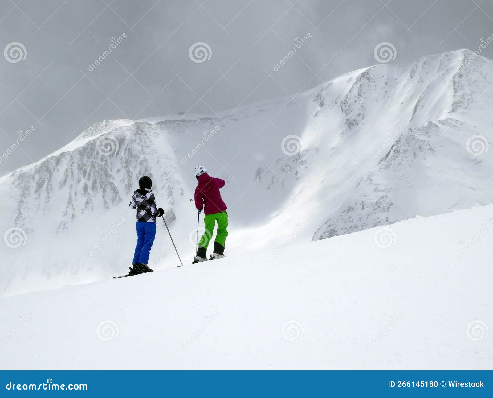 Two Skiers Standing on the Snowy Mountainside with the White Mountains ...