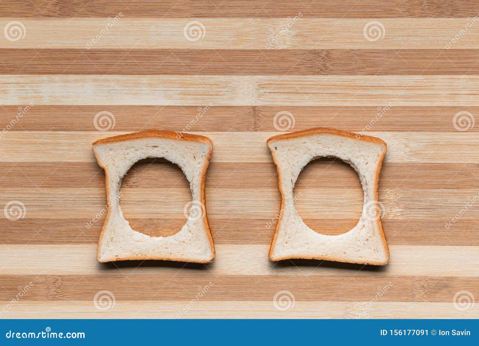 Two Slices of Bread with Their Centers Cut on a Brown Table, Shot from ...