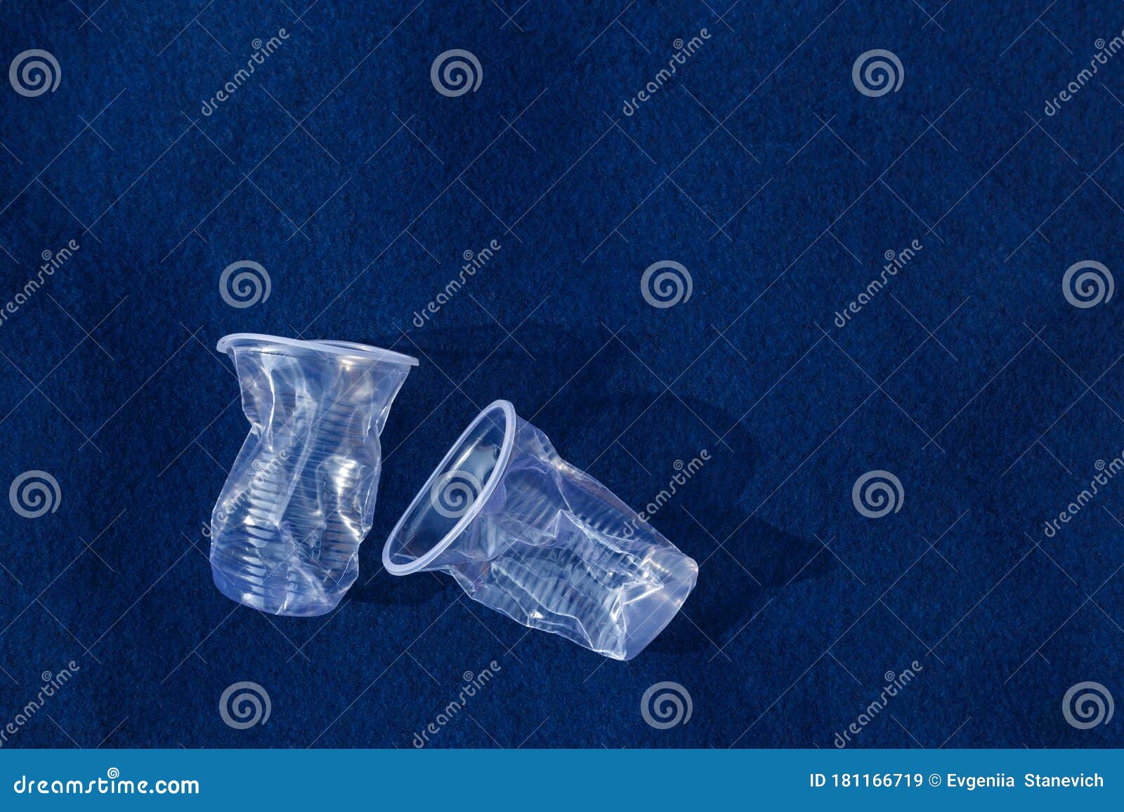 Two Smashed Transparent Plastic Cups on a Blue Background with Copy ...