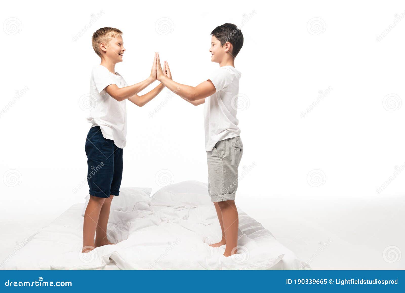 Two Smiling Brothers Clapping Hands while Standing on Bed Stock Image ...