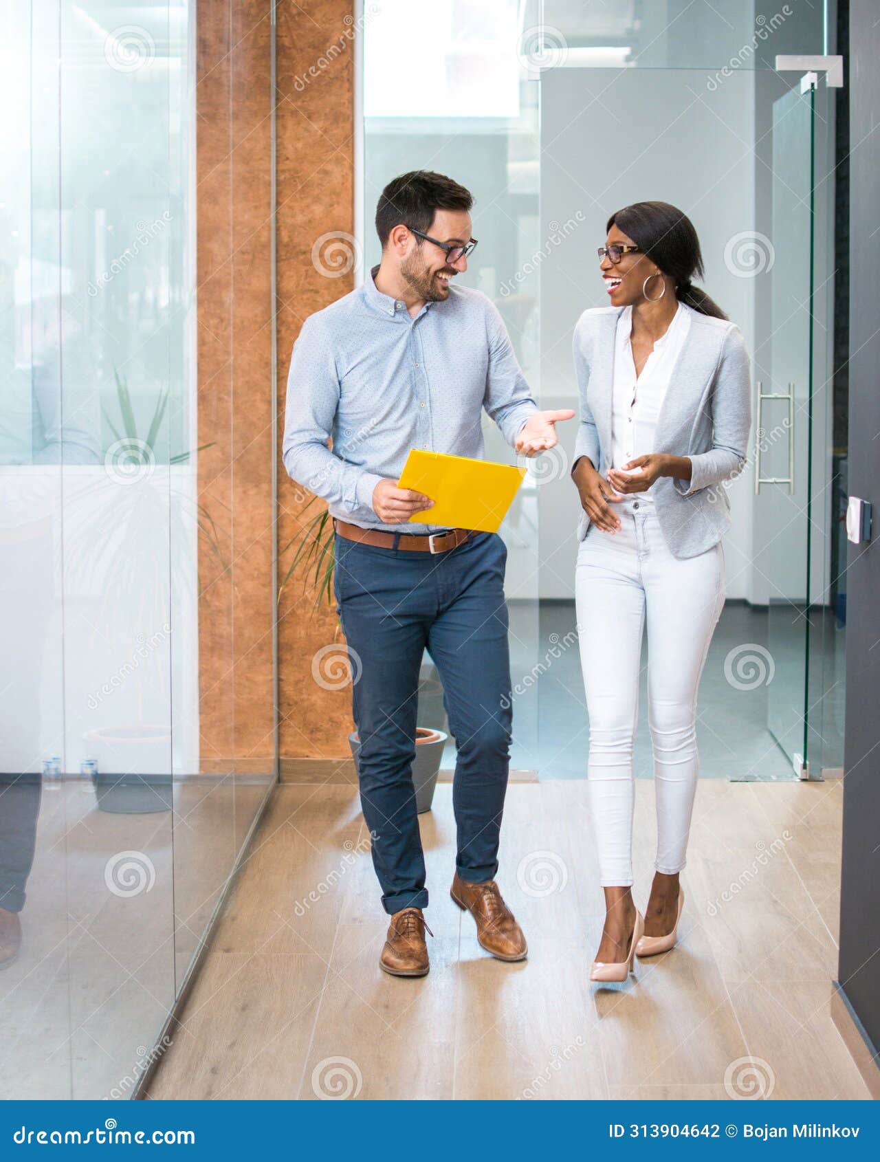 Two Smiling Business People Walking through Office Hall and Talking ... Two Smiling Business People Walking through Office Hall and Talking ...
