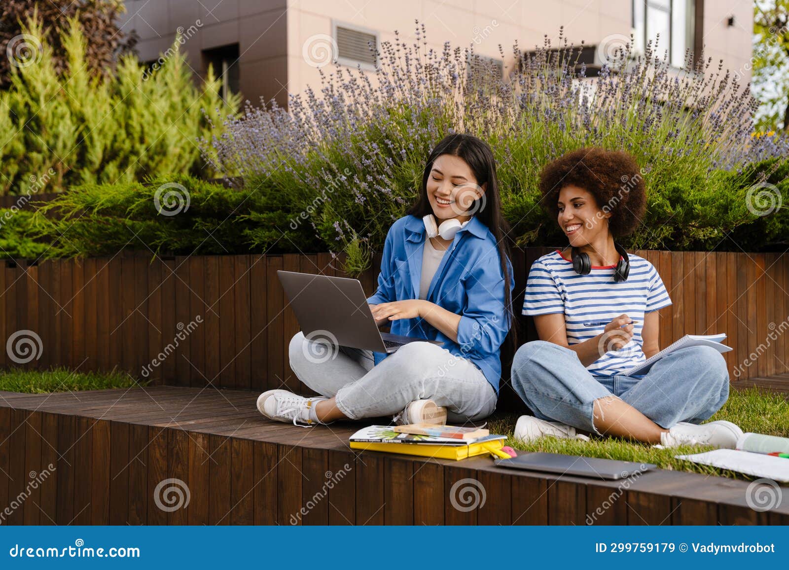 Two Smiling Female Students Using Laptop and Writing Down Notes while ...
