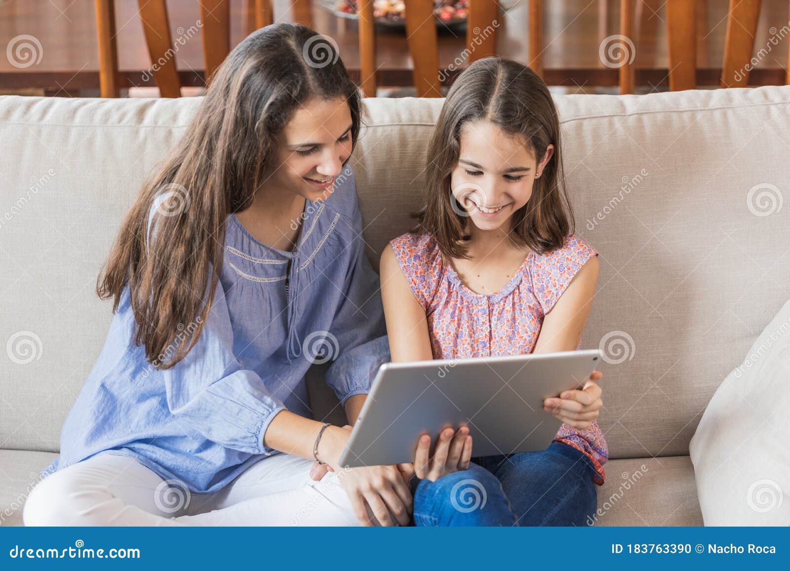 Two Smiling Girls Looking at the Tablet at Home Stock Photo - Image of ...