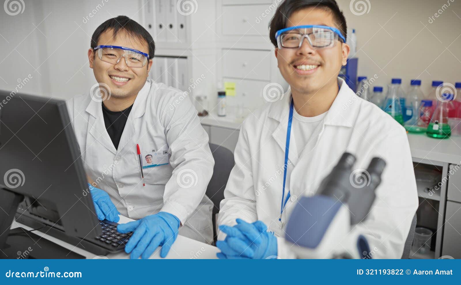 Two Smiling Men in Lab Coats and Safety Glasses Working Together with a ...