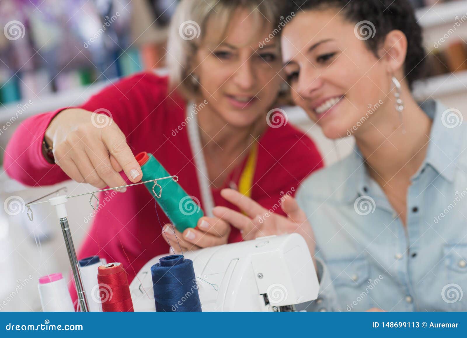 Two Smiling Women Using Sewing Machine while Holding Bright Fabric ...
