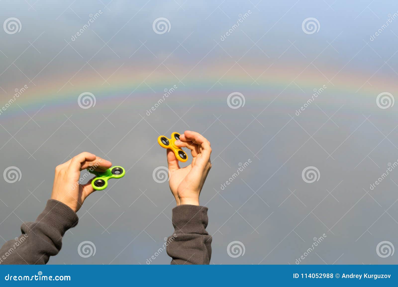 Two Spinners in the Hands on the Background of the Rainbow Stock Photo ...