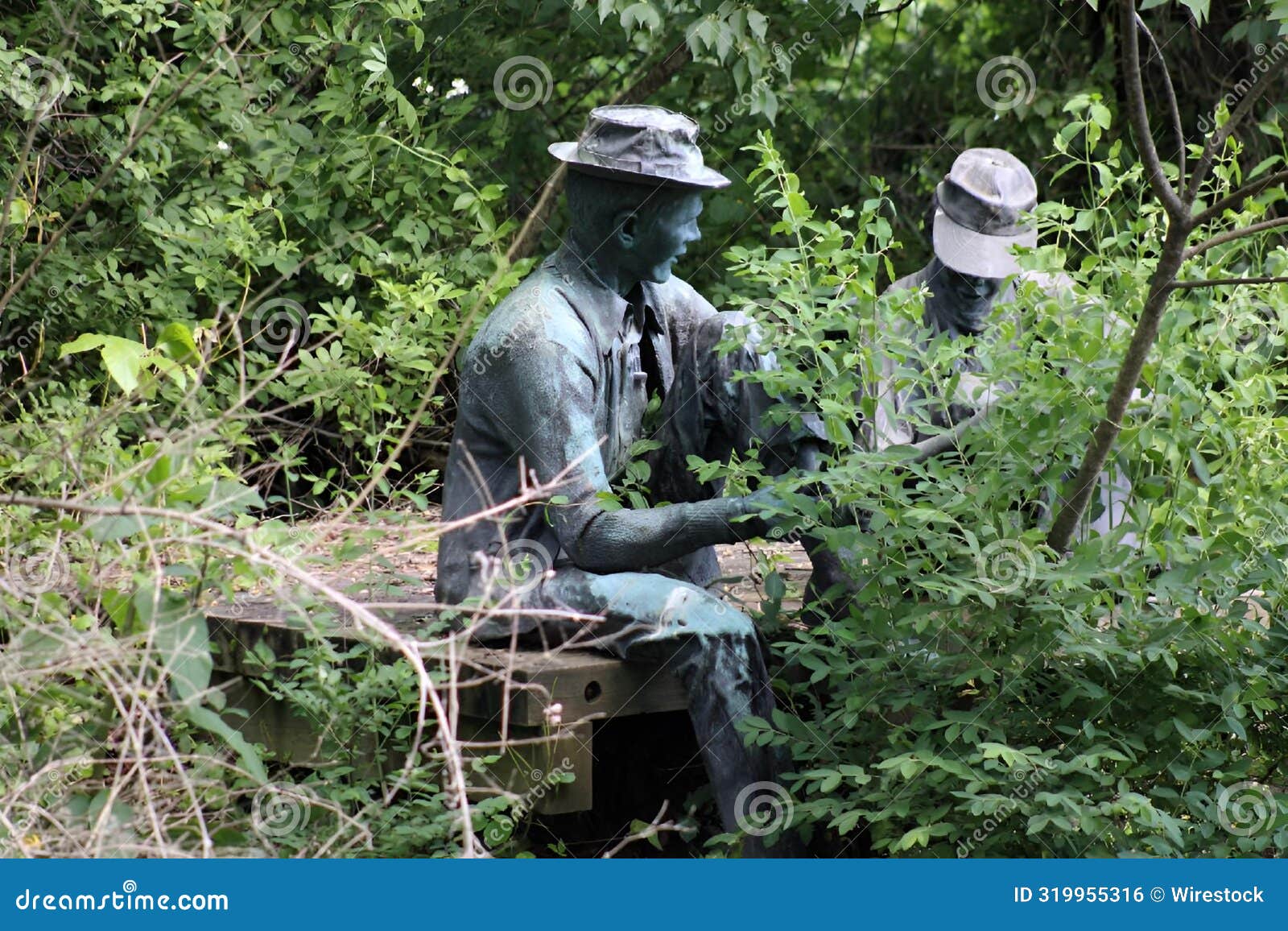 Two Statue Figures Sit in the Middle of Lush Vegetation and Trees ...