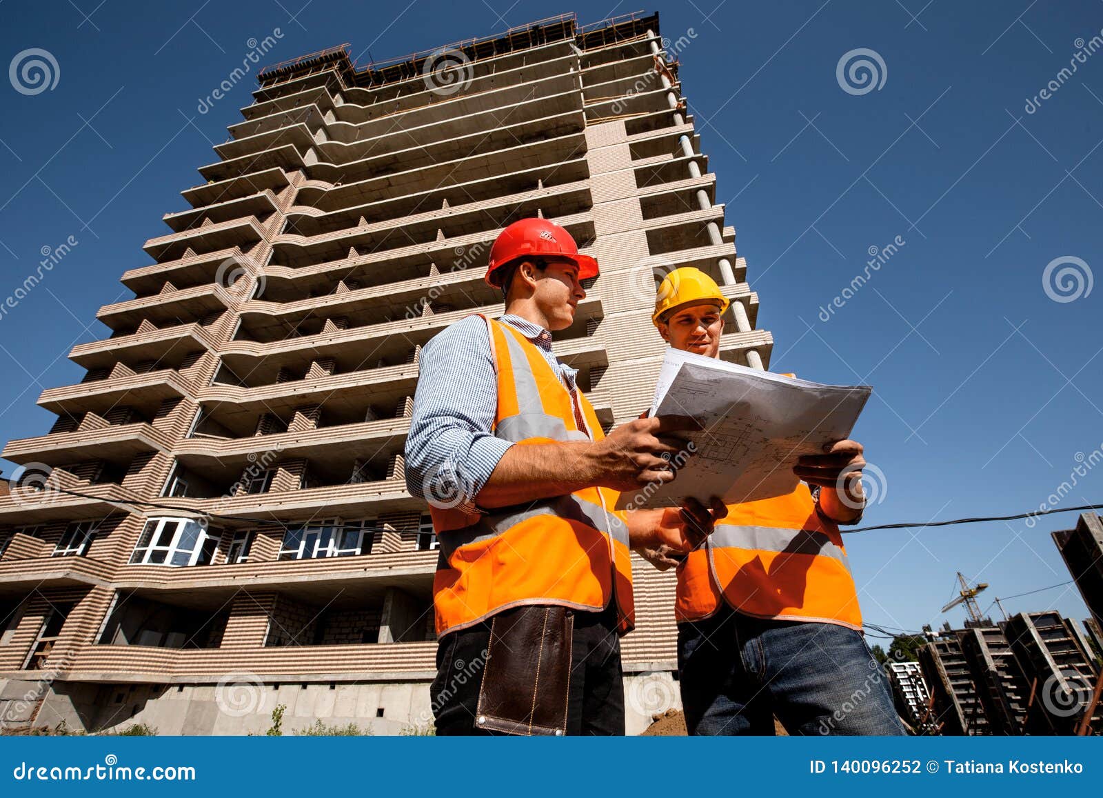 Two Structural Engineers Dressed in Shirts, Orange Work Vests and ...