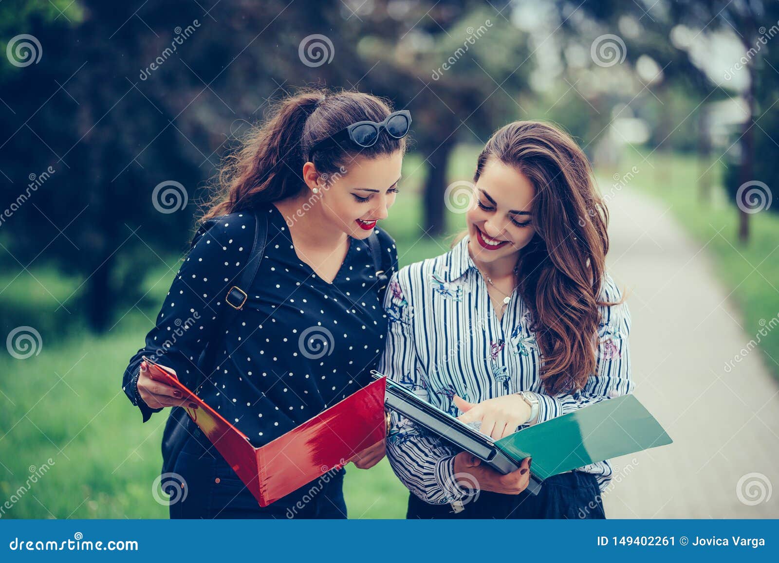 Two Students Learning Reading a Notebook and Commenting in the Street ...