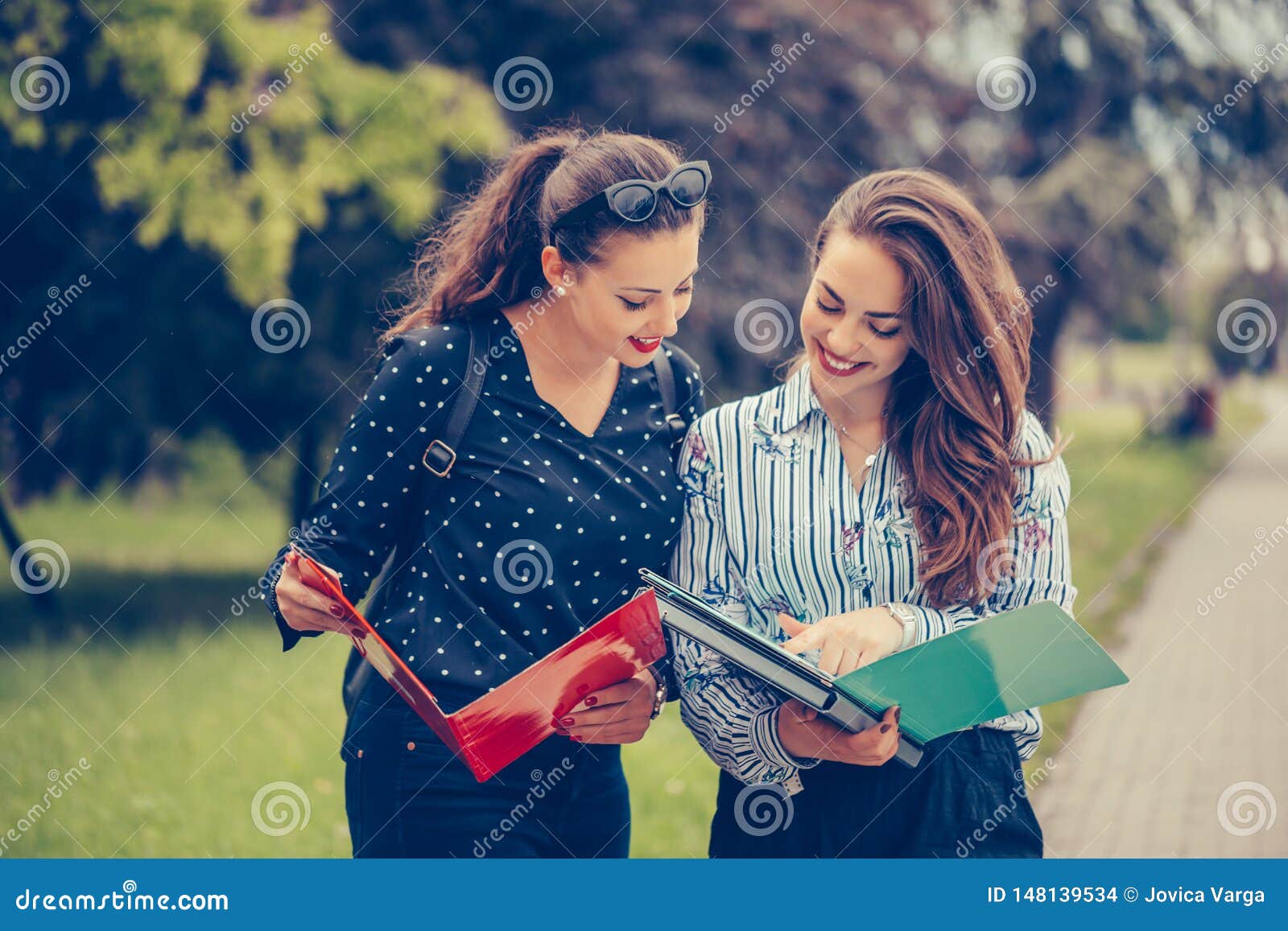 Two Students Learning Reading a Notebook and Commenting in the Street ...