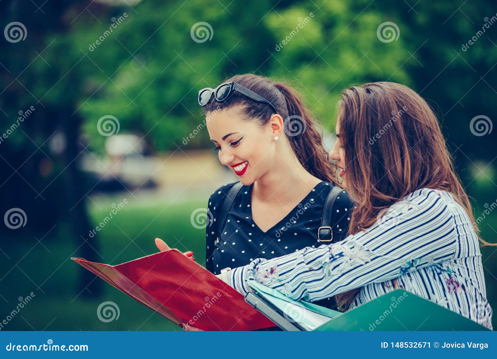 Two Students Learning Reading a Notebook and Commenting in the Street ...