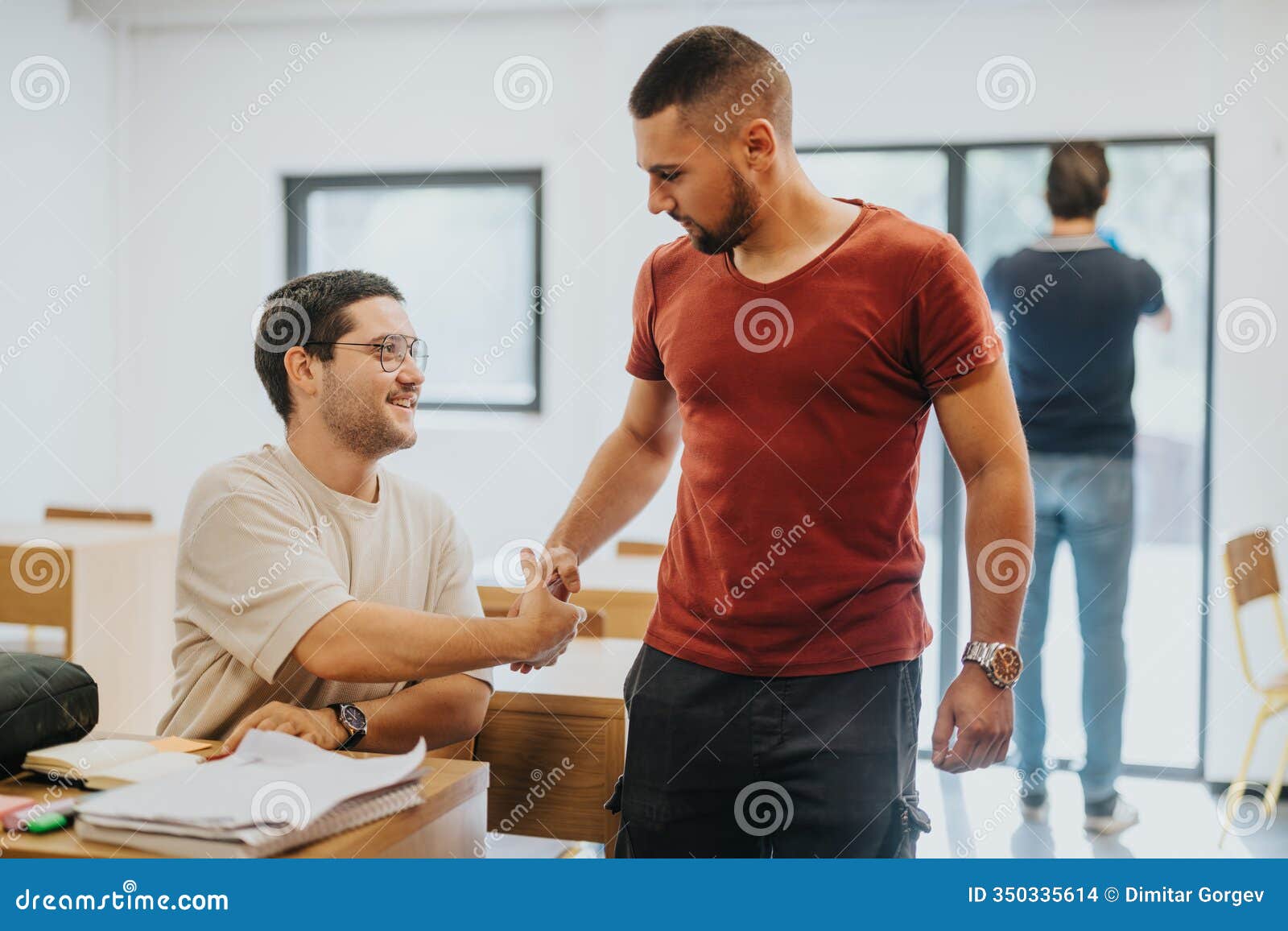 Two Students Shaking Hands in a Bright Classroom Setting Stock Photo ...